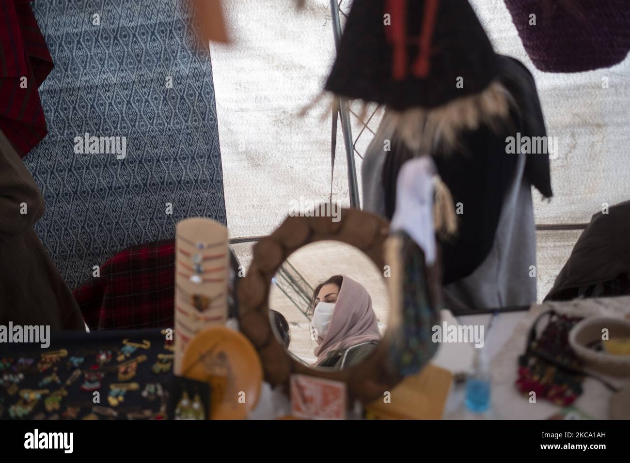 An Iranian woman wearing a protective face mask looks on while visiting ...