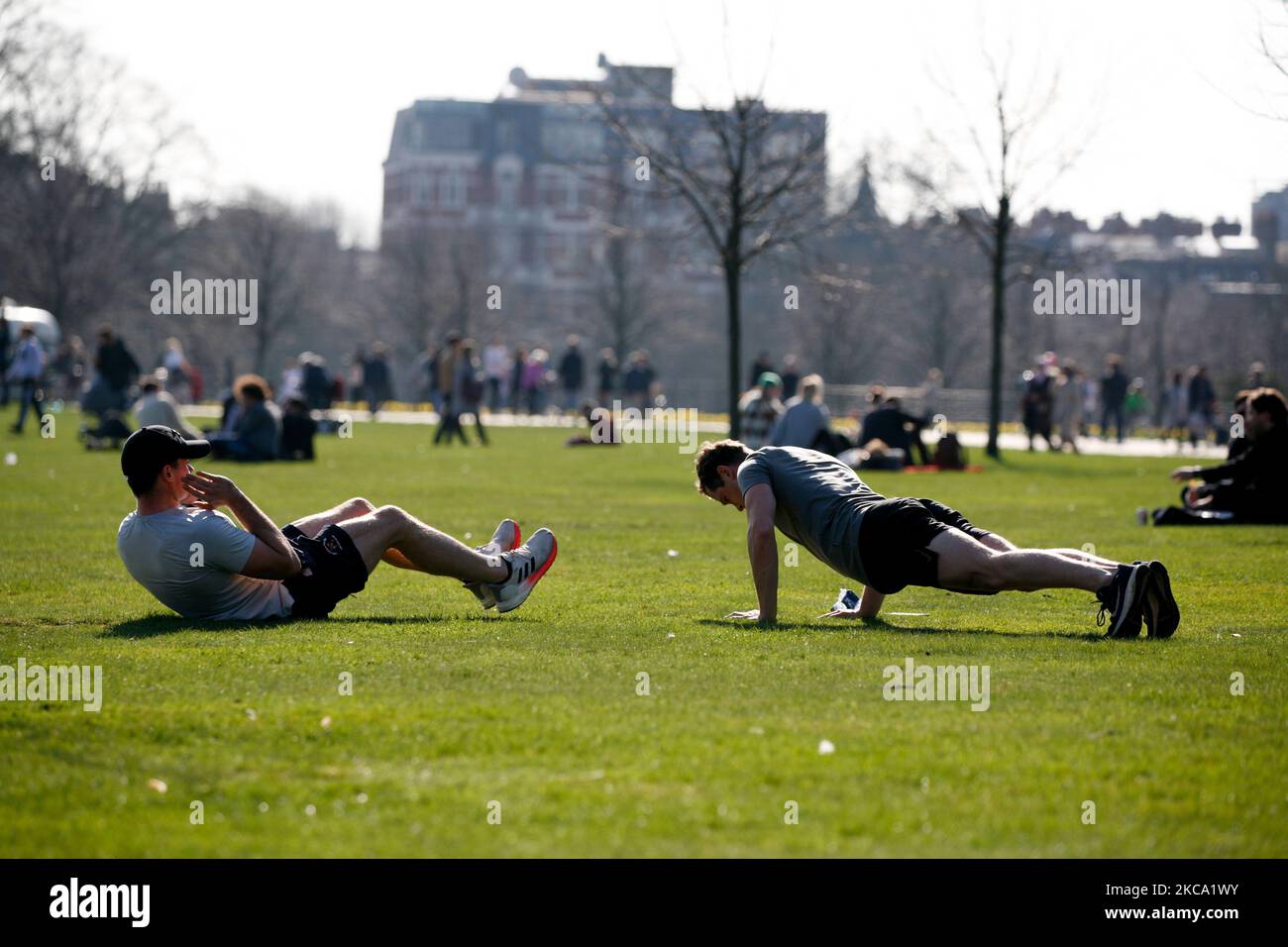 Two men exercise in spring sunshine in Kensington Gardens in London ...
