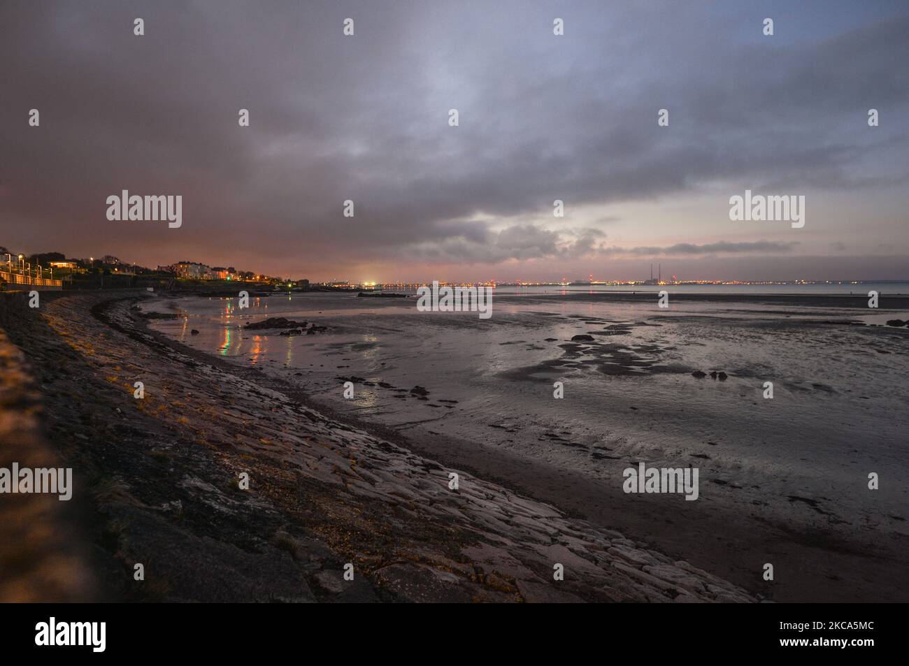 View of Dublin's Seapoint Beach at dusk, set against the Poolbeg ...