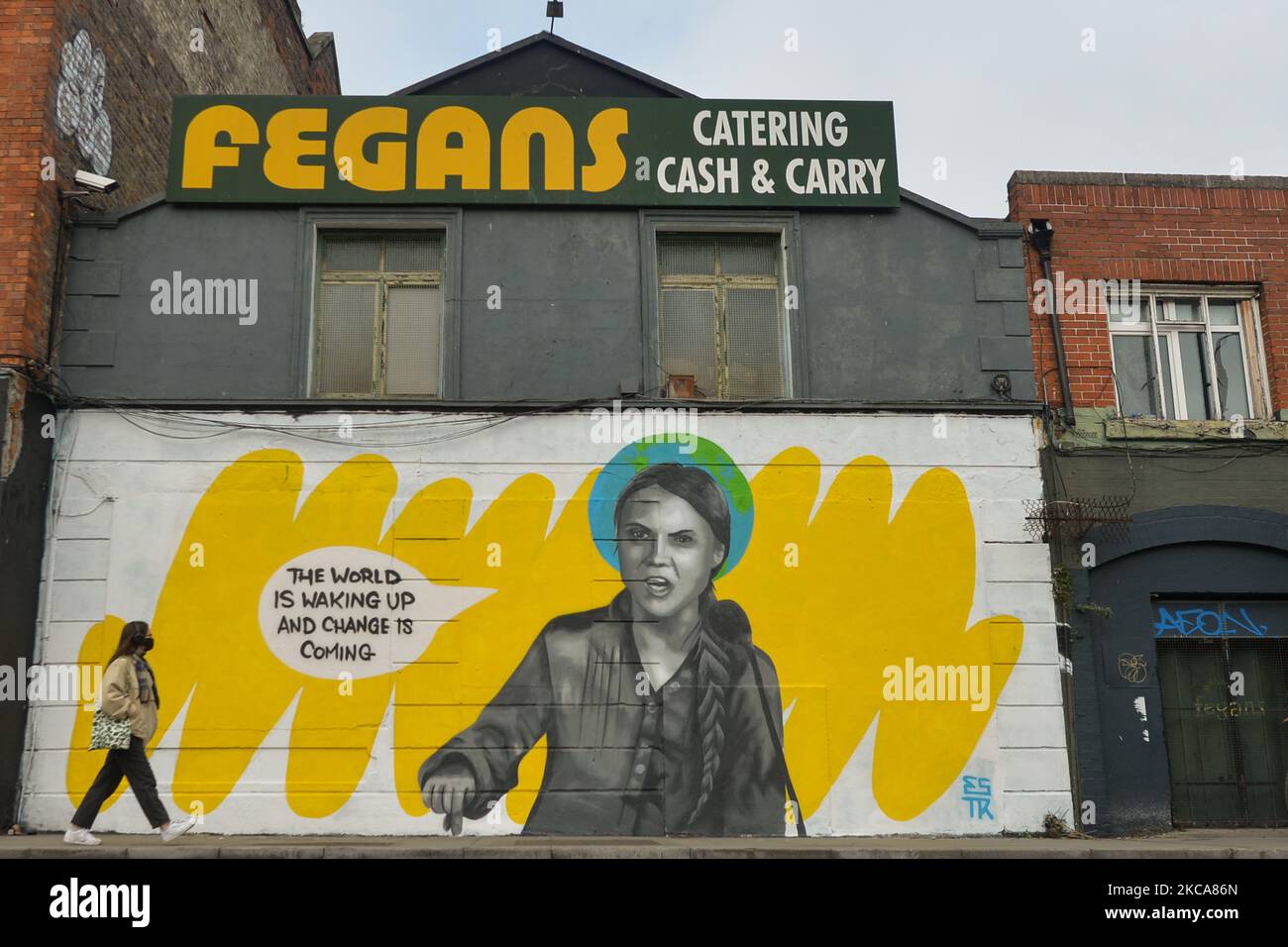 A woman wearing a face mask walks by a new mural in Dublin by Irish artist, Emmalene Blake ...