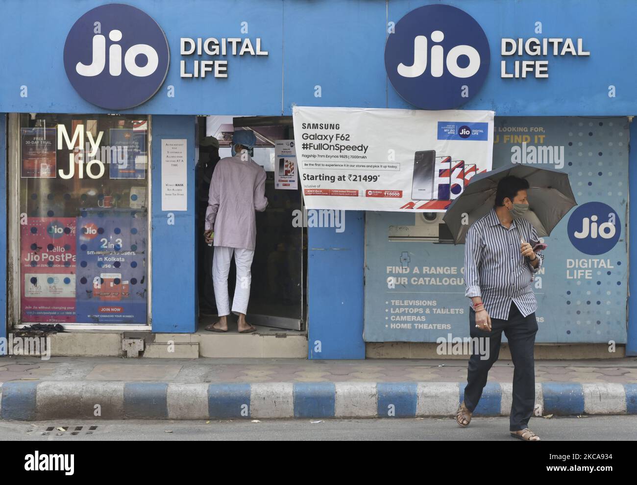 A man with an umbrella in front of a Jio store in Kolkata, India, 03 ...