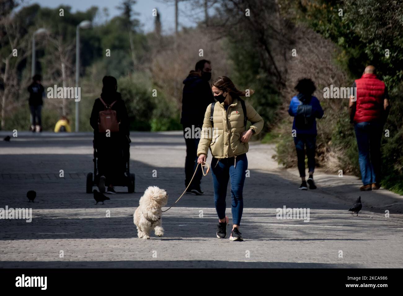 A woman with his dog seen walking at Acropolis heel wearing protected ...