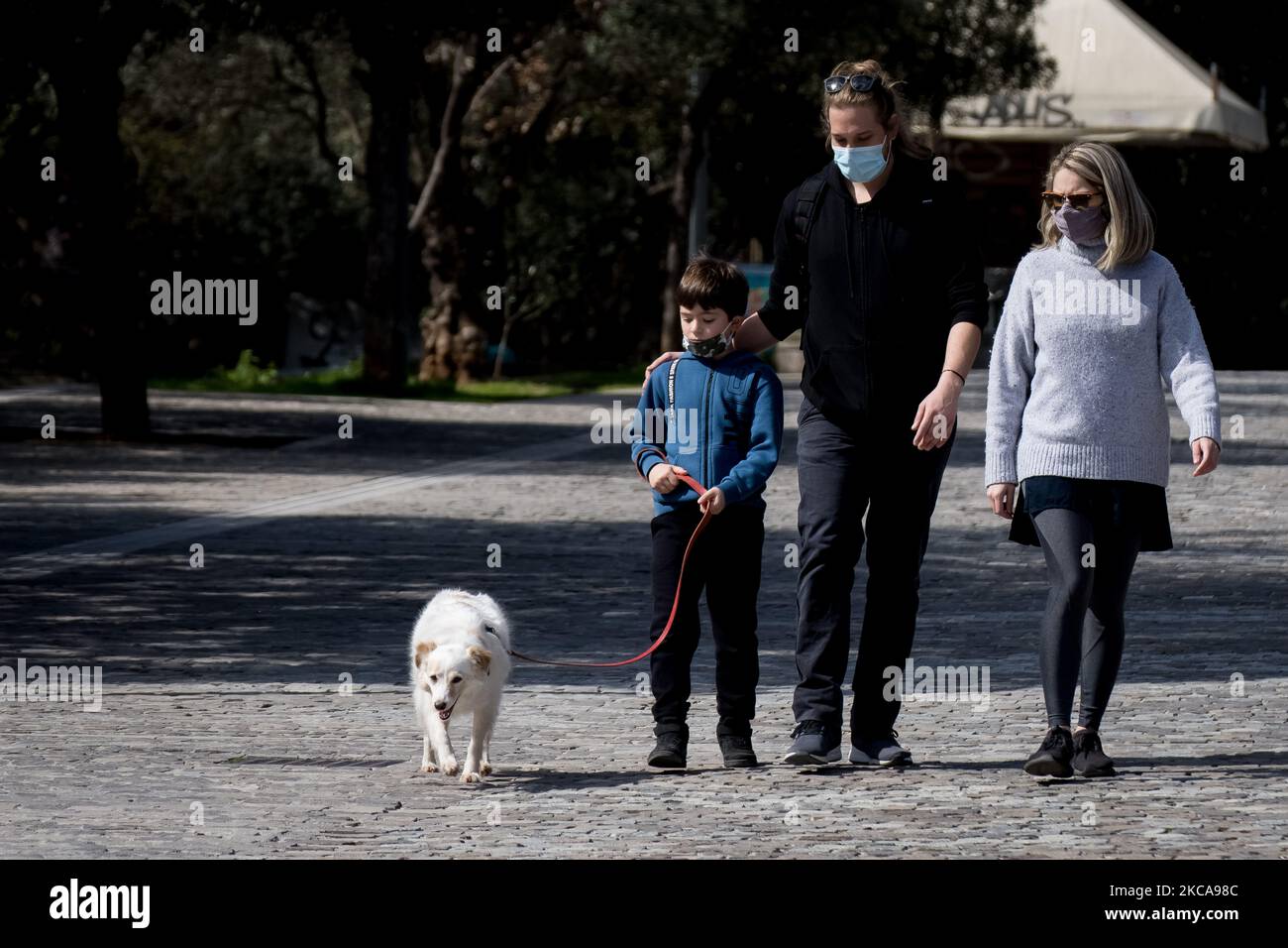 A kid with his dog seen walking with his family at Acropolis heel ...