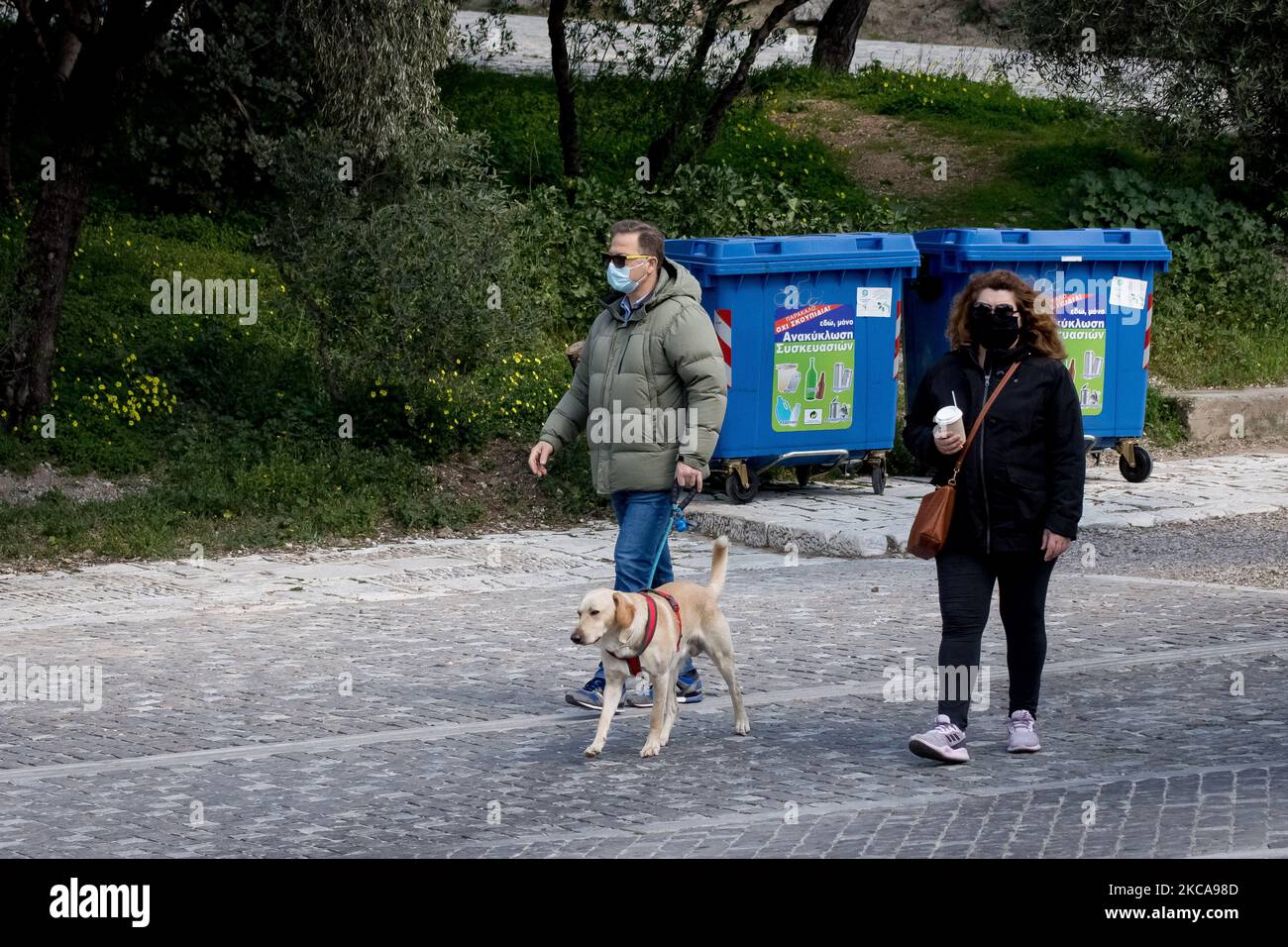 A man with his dog seen walking at Acropolis heel wearing protected ...