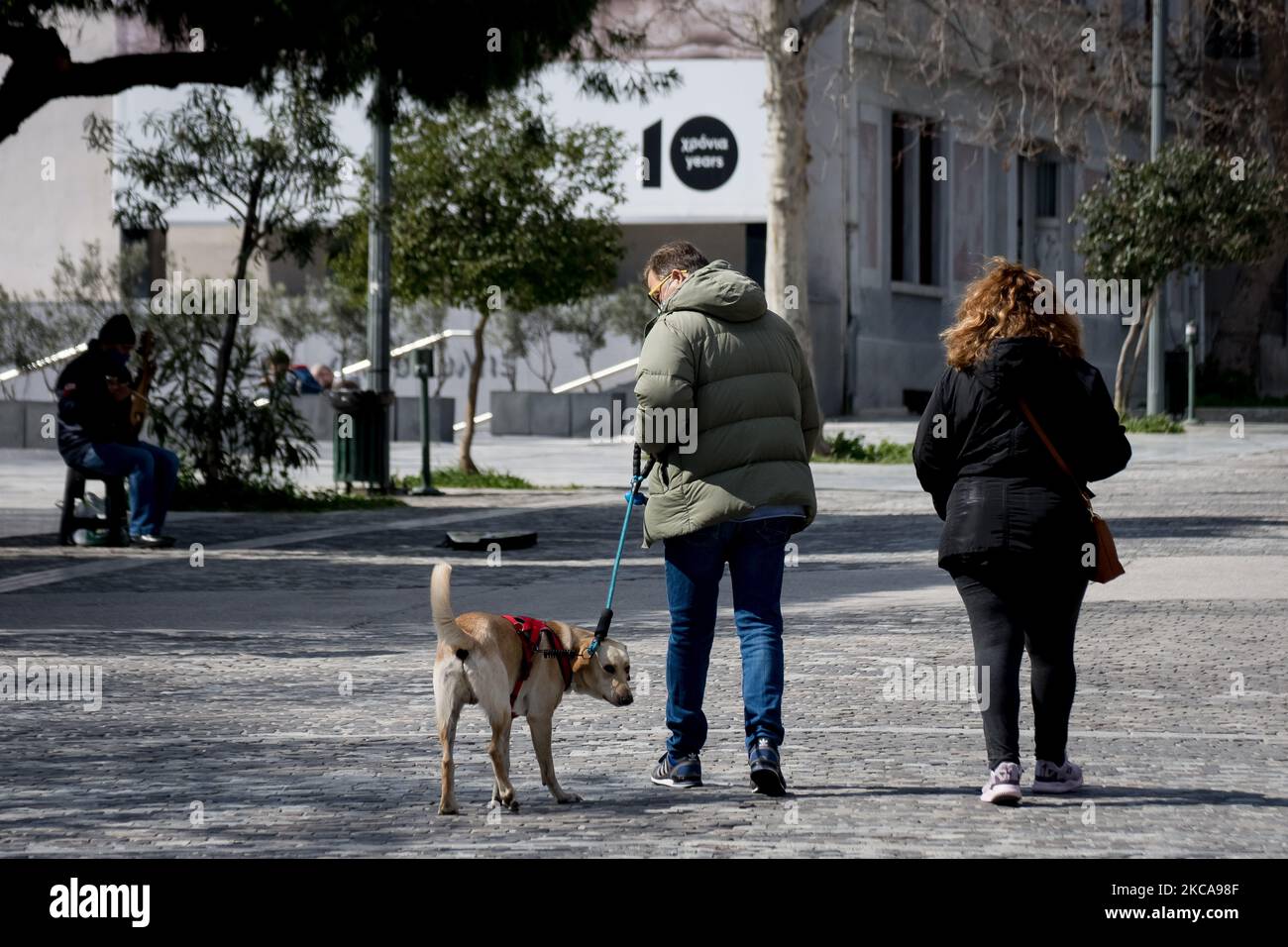 A man with his dog seen walking at Acropolis heel wearing protected ...