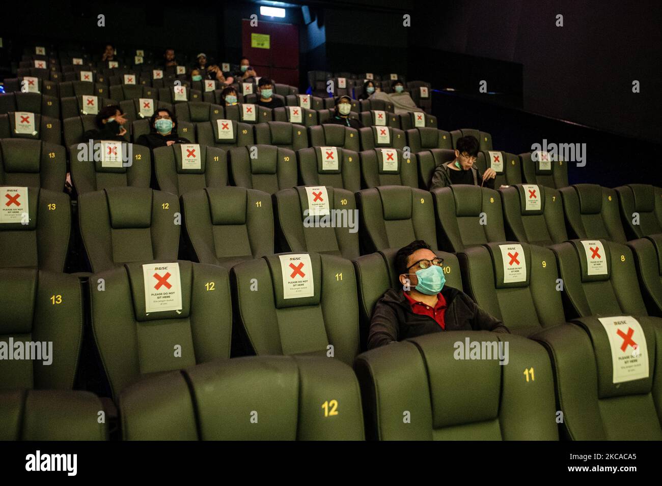 People wear protective masks sit inside a movie theatre in Kuala Lumpur ...