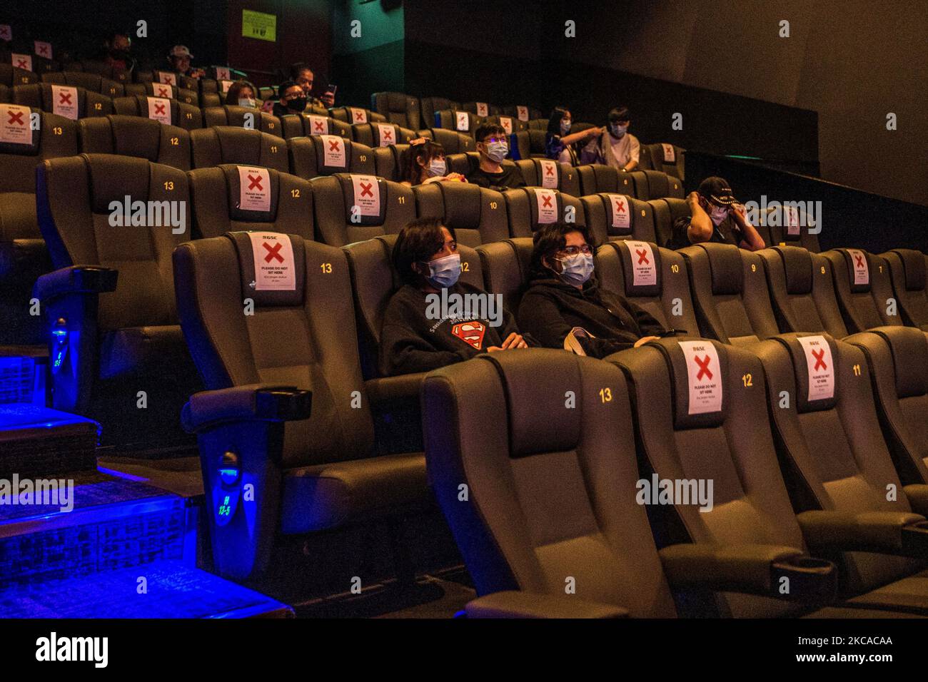 People wear protective masks sit inside a movie theatre in Kuala Lumpur ...