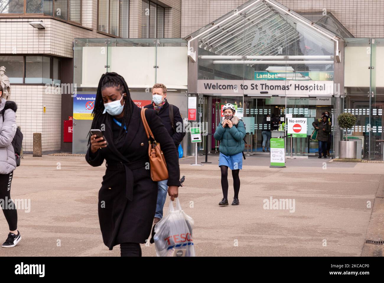 Patients and NHS staff walk in front of St Thomas Hospital located in ...