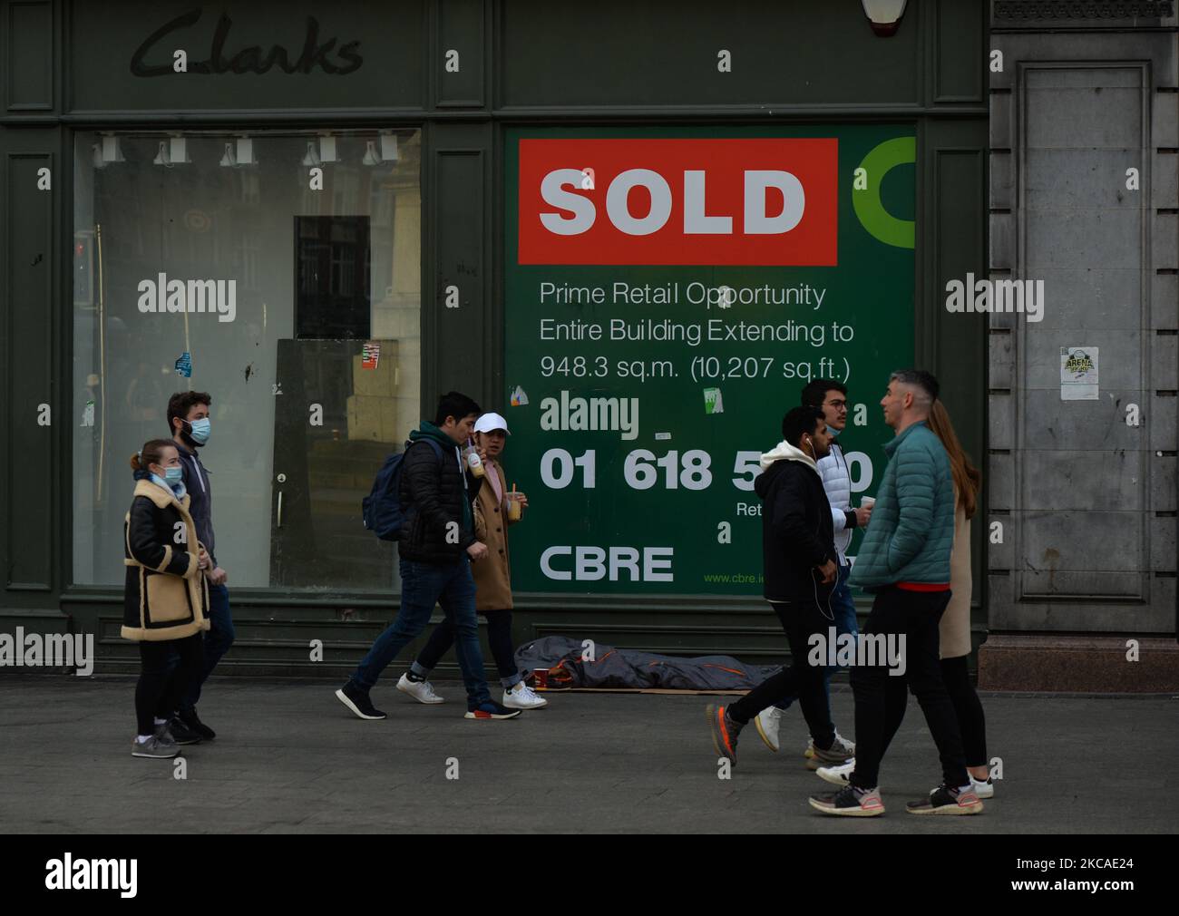 People walk by a rough sleeper outside a closed Clarks shop in Dublin ...