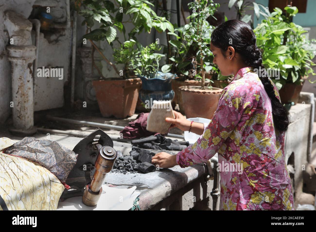 Jain woman prepares a coal powered iron before ironing clothes outside ...