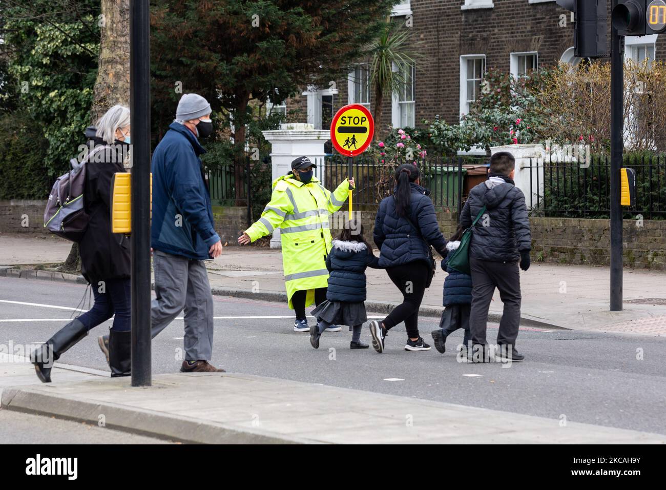 A family with school children is supported to cross the street after ...