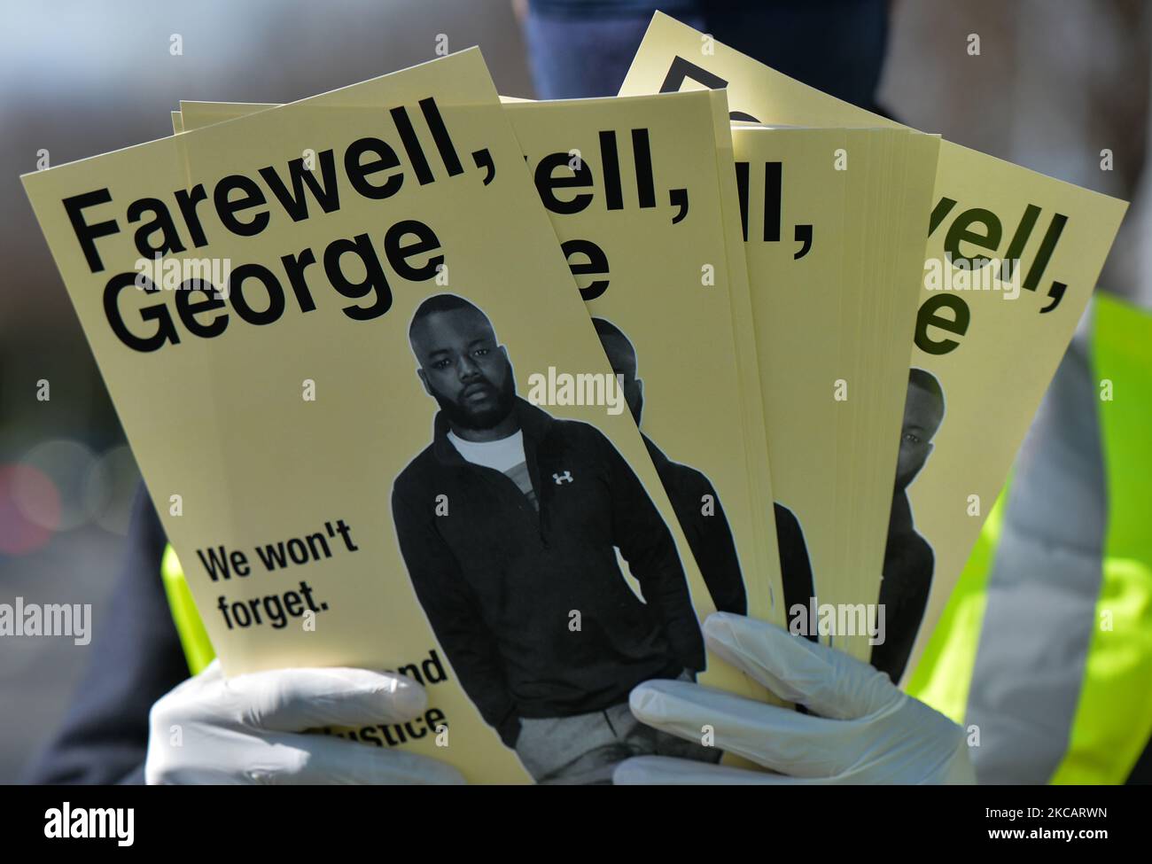 A man holds leaflets reading 'Farewall George' as many people gather ...