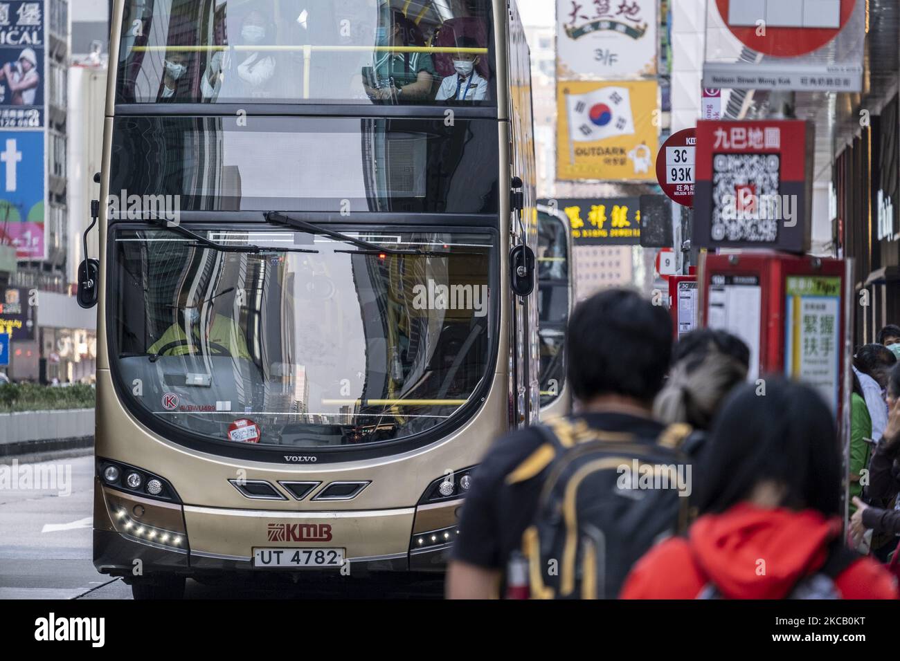 Commuters wait for buses at a bus station as a bus operated by KMB ...