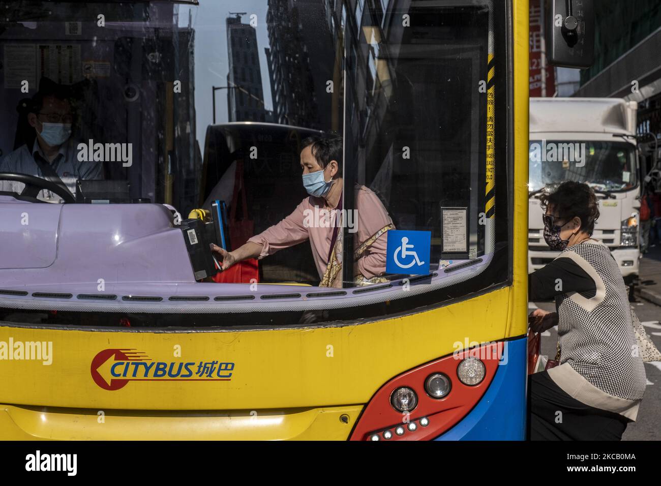 A women wearing a face mask pays with octopus as she board a bus ...