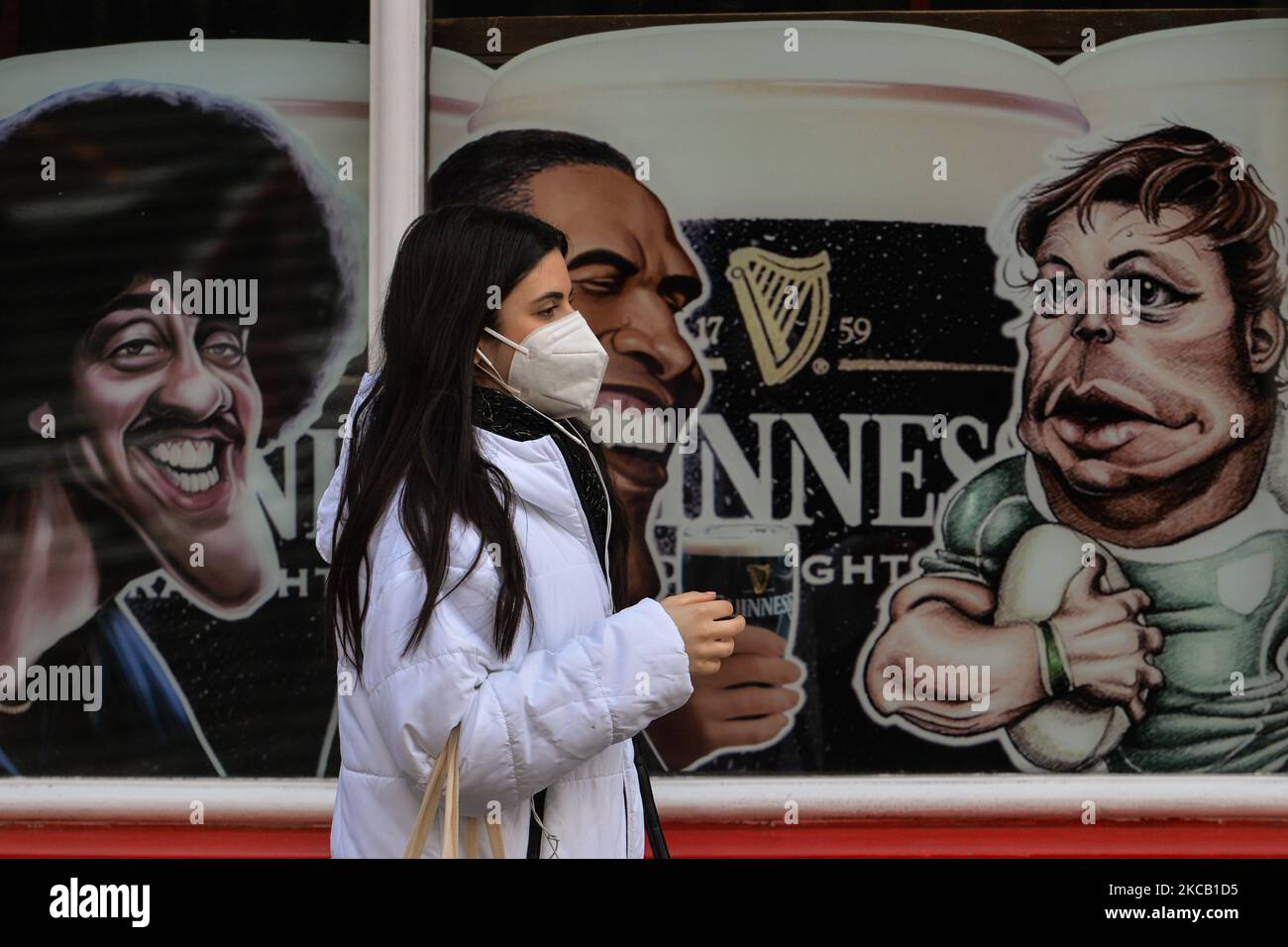 A man wearing a face mask walks by a closed pub in Dublin city center ...