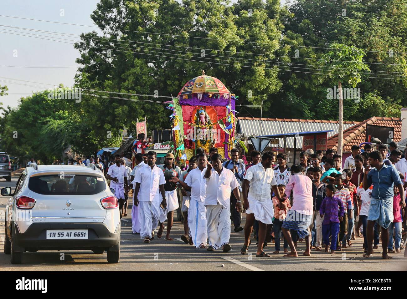 Hindu devotees escort a large clay idol of Lord Ganesh along the road ...