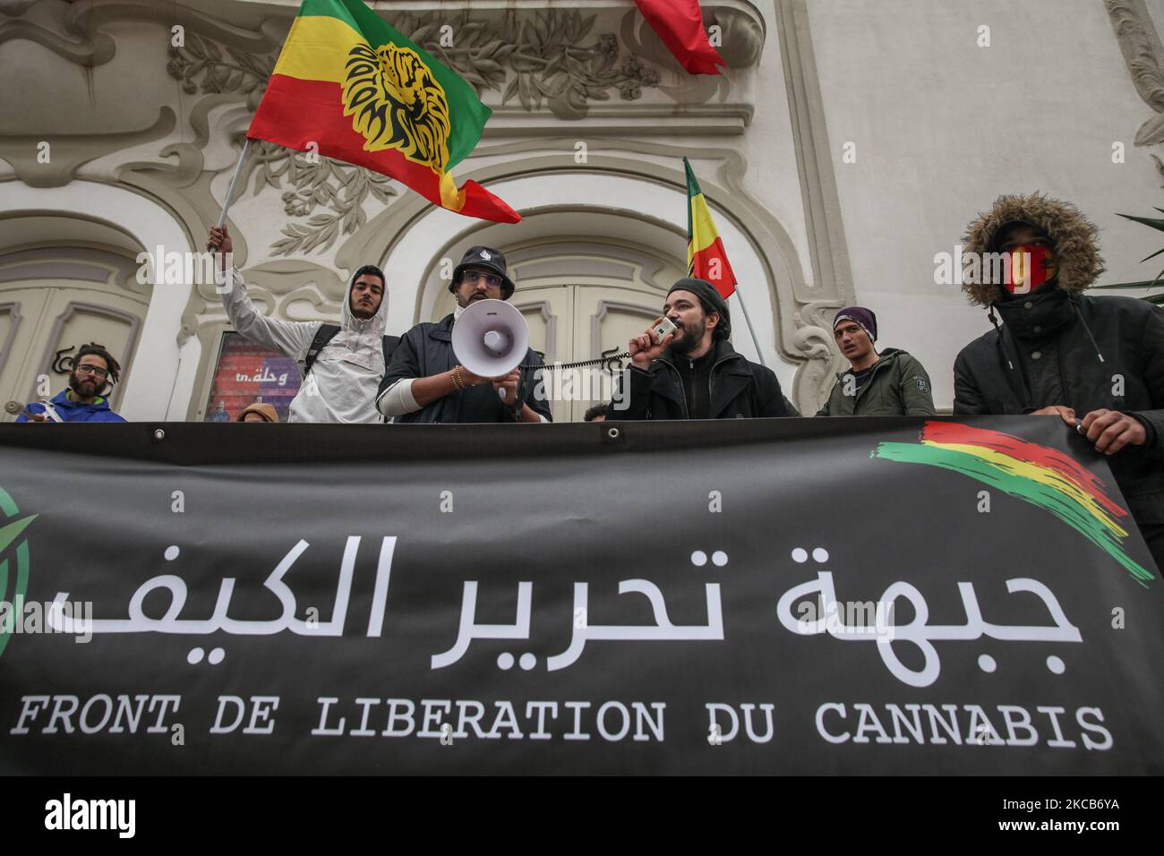 Protesters wave flags as they hold a banner with a drawing of cannabis ...