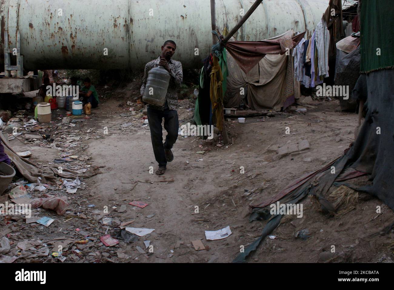 A man carries plastic containers filled with water coming out of a ...