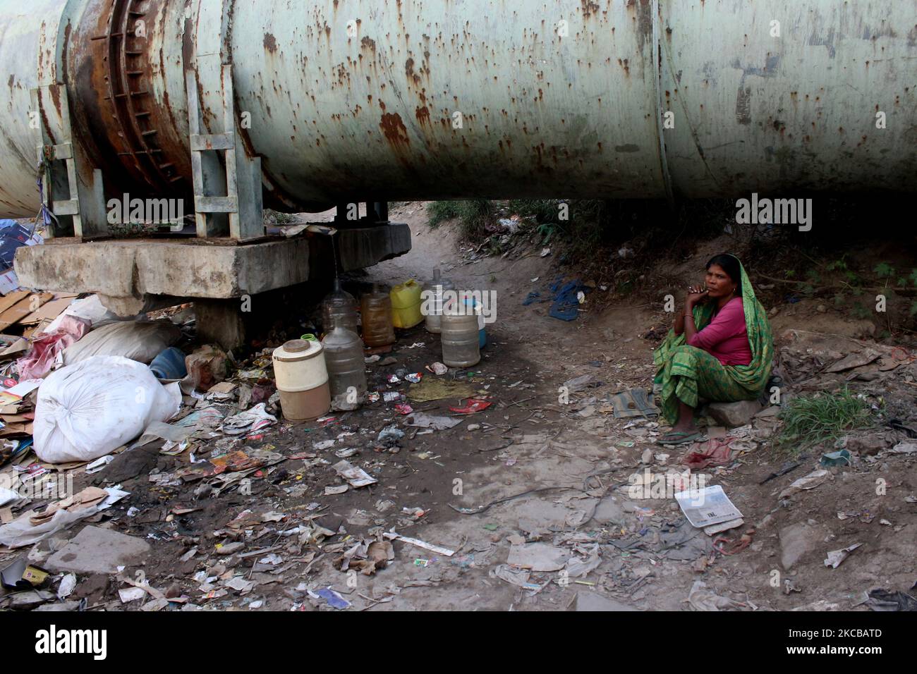 A woman waits while filling up her plastic containers with water coming ...