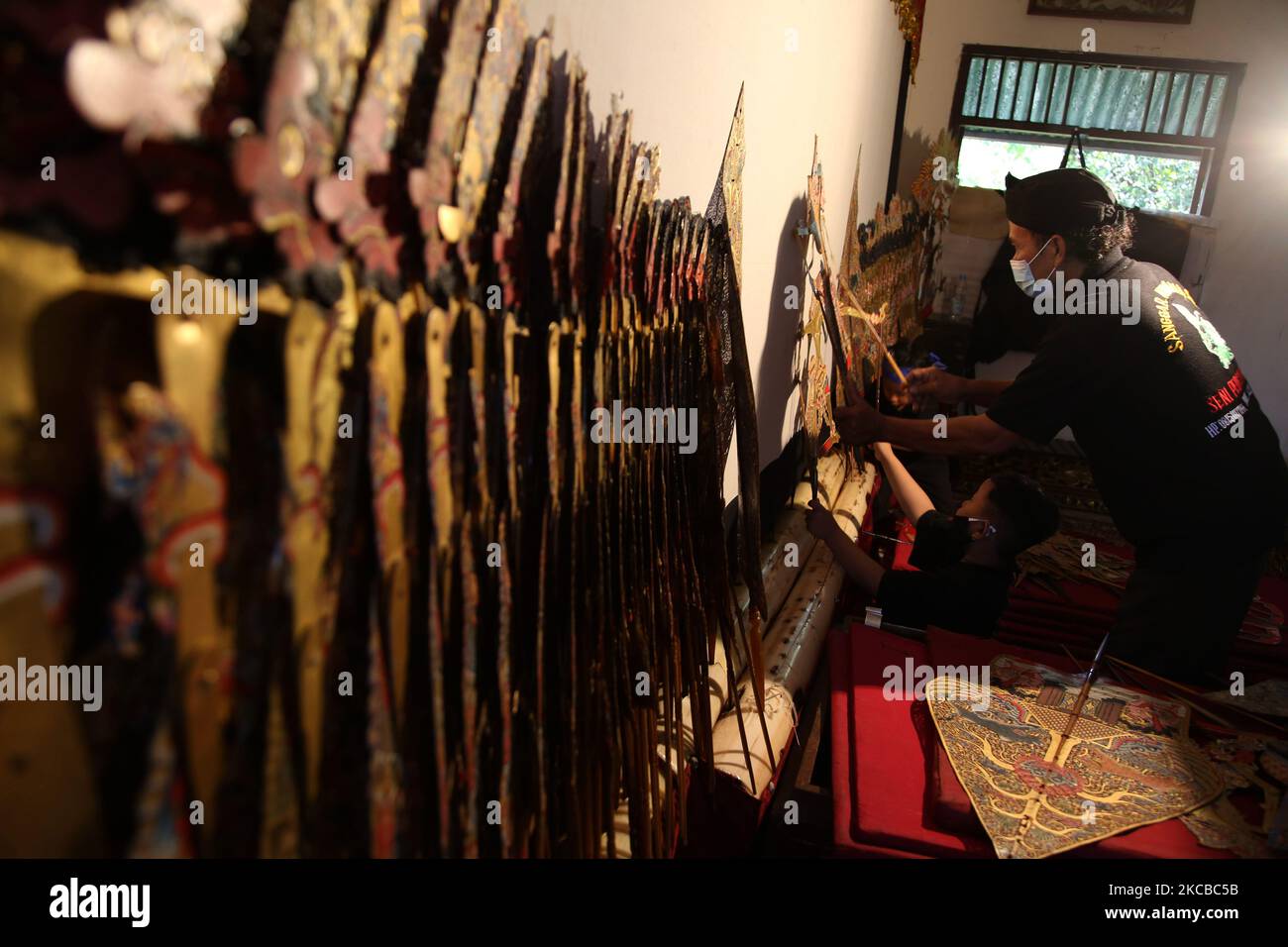 A child accompanied by a teacher learns to perform Javanese Wayang as a ...