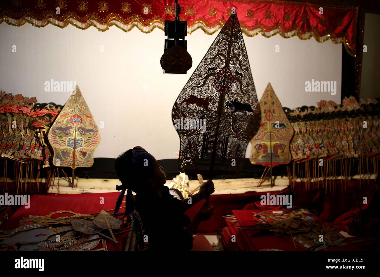 A child accompanied by a teacher learns to perform Javanese Wayang as a ...