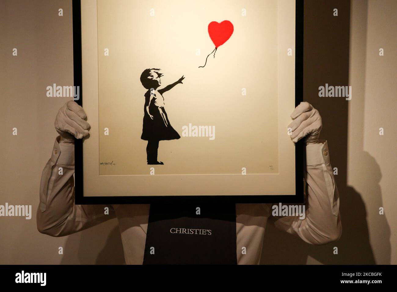 An art handler poses holding 'Girl with Balloon', by British artist ...