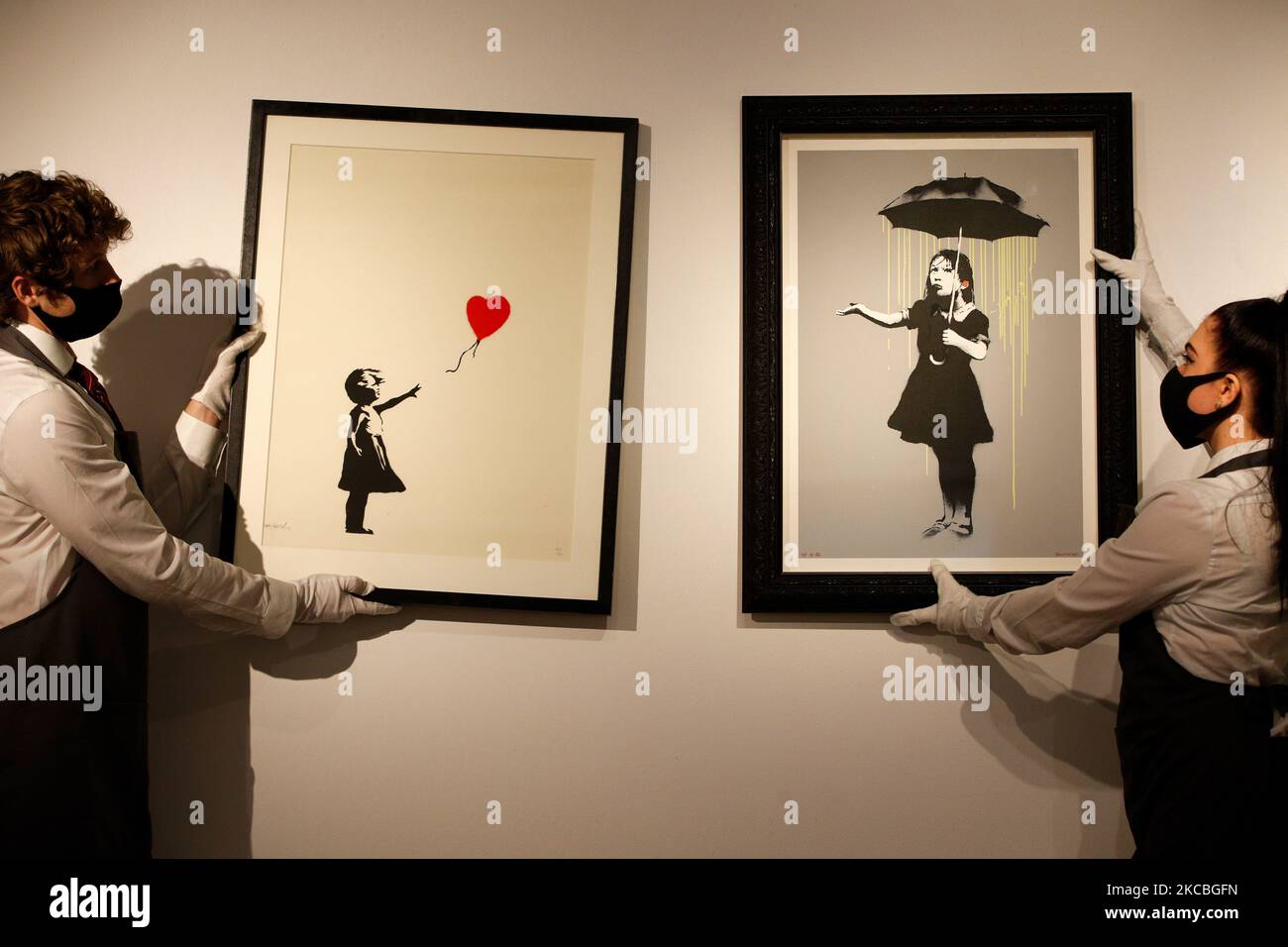 Art handlers pose holding works by British artist Banksy 'Girl with ...