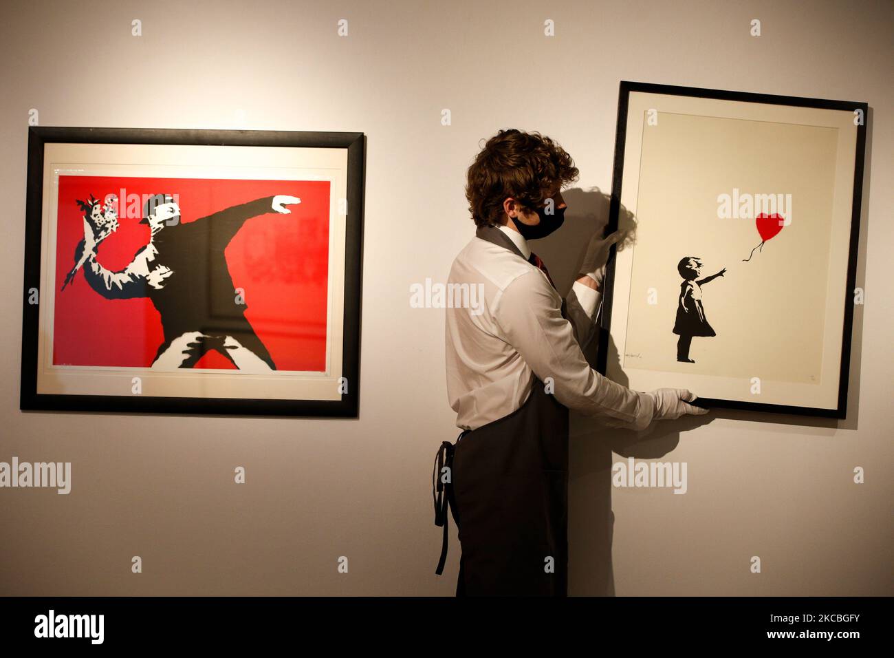 An art handler poses holding work by British artist Banksy 'Girl with ...