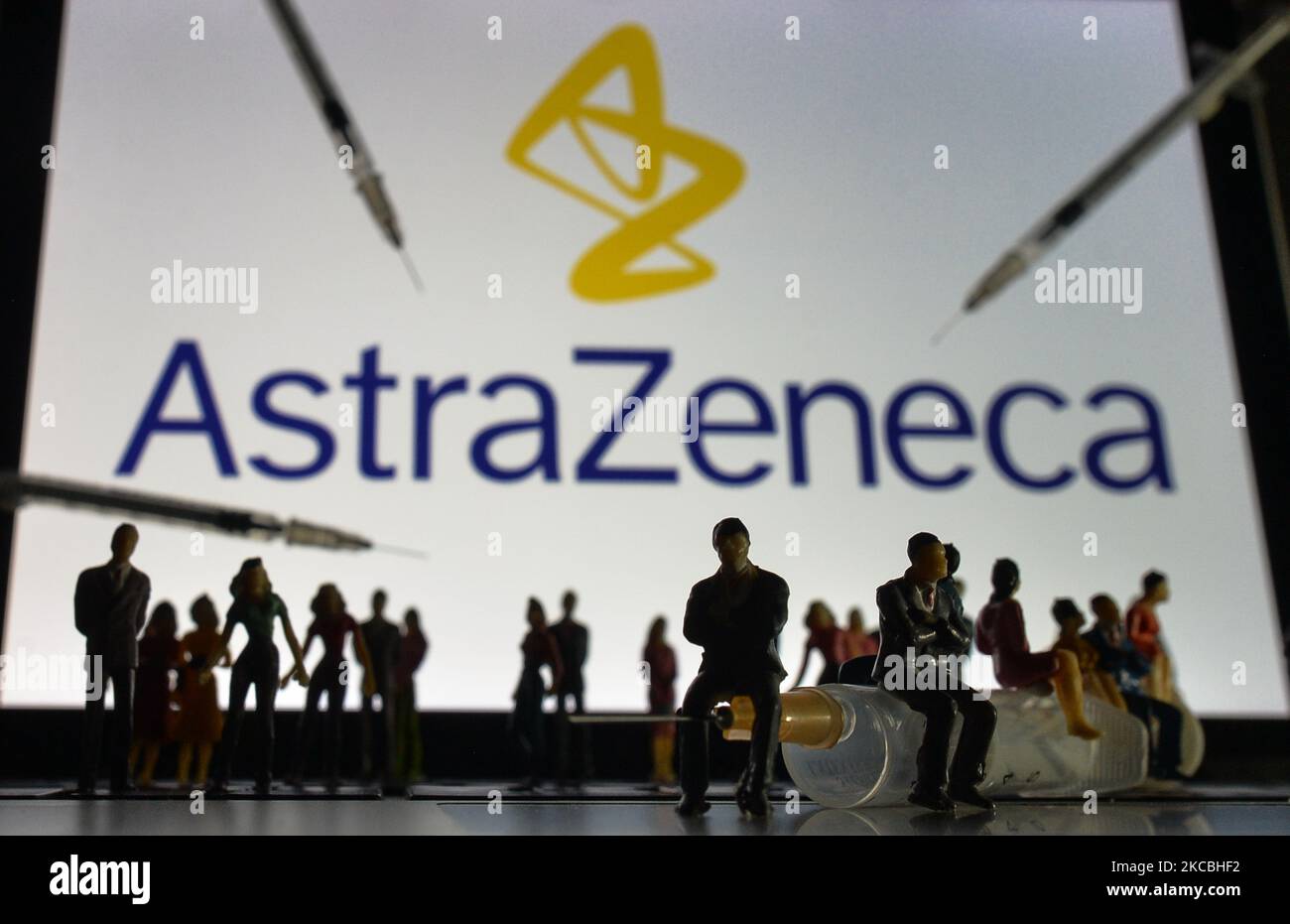 Medical syringes and small figurines of people are seen in front of the ...