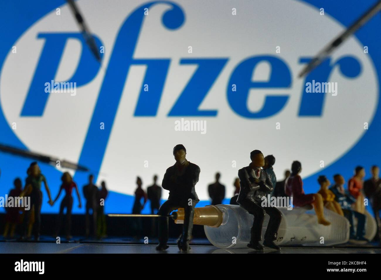 Medical syringes and small figurines of people are seen in front of the ...