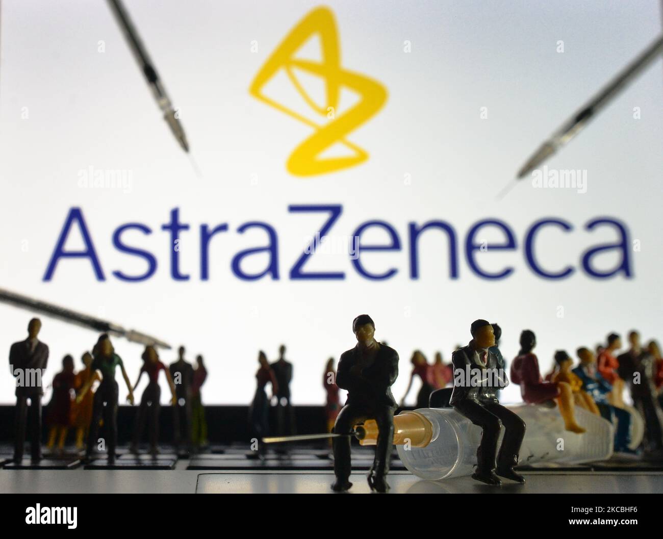 Medical syringes and small figurines of people are seen in front of the ...