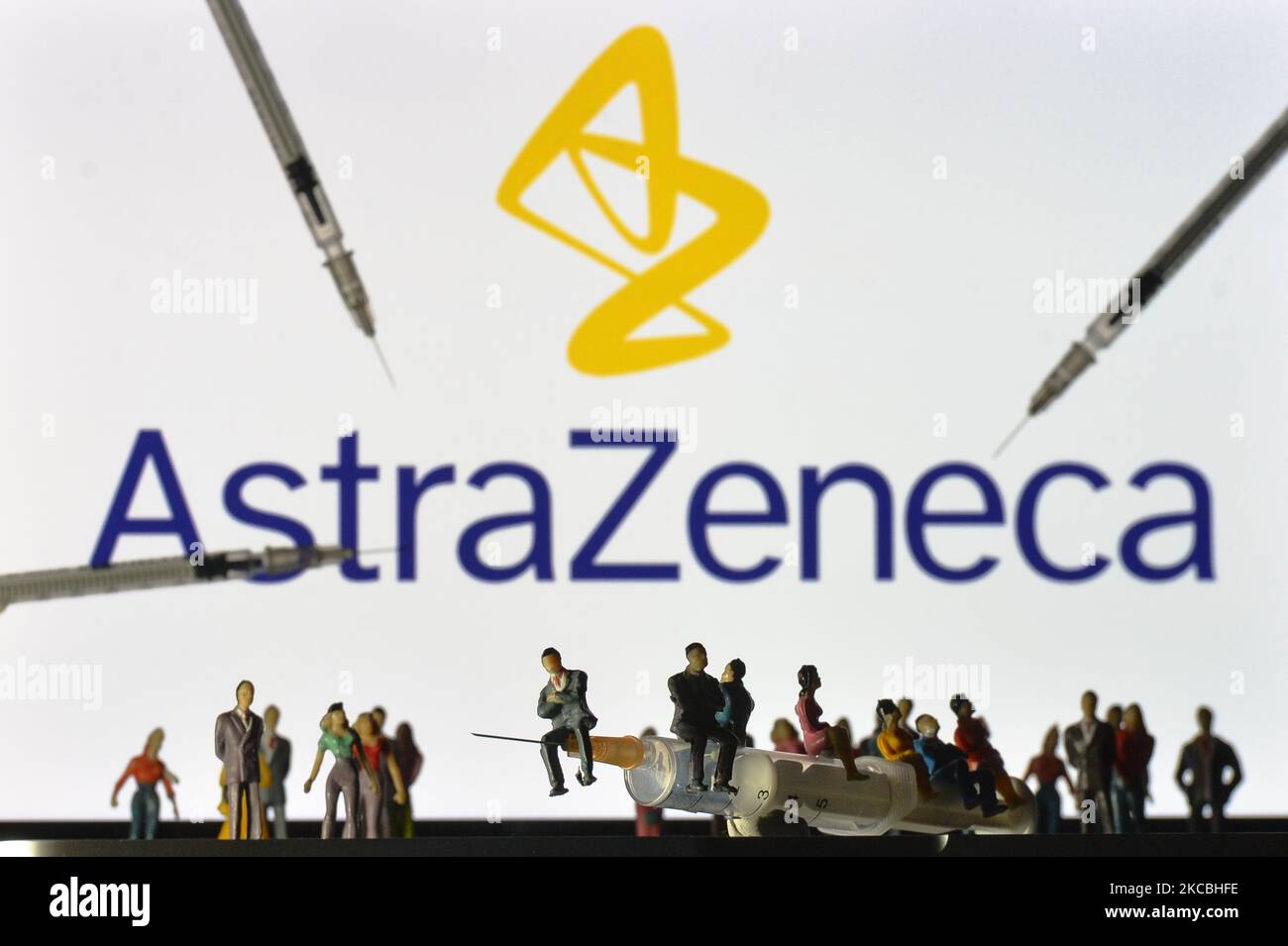 Medical syringes and small figurines of people are seen in front of the ...