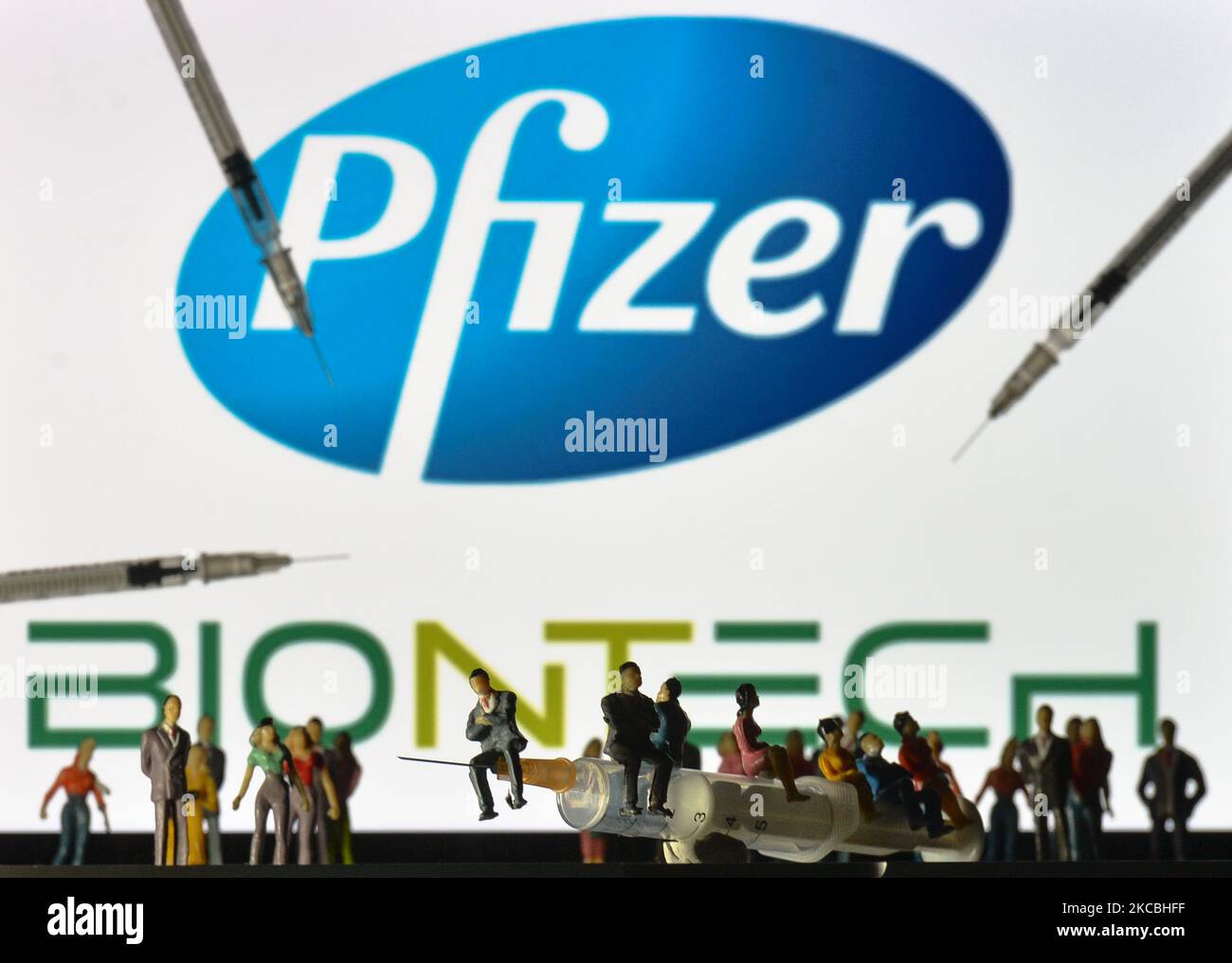 Medical syringes and small figurines of people are seen in front of the ...