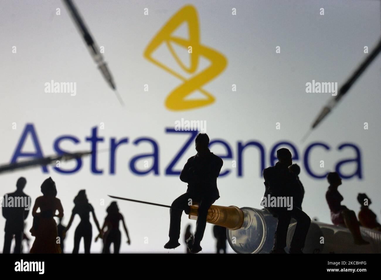 Medical syringes and small figurines of people are seen in front of the ...
