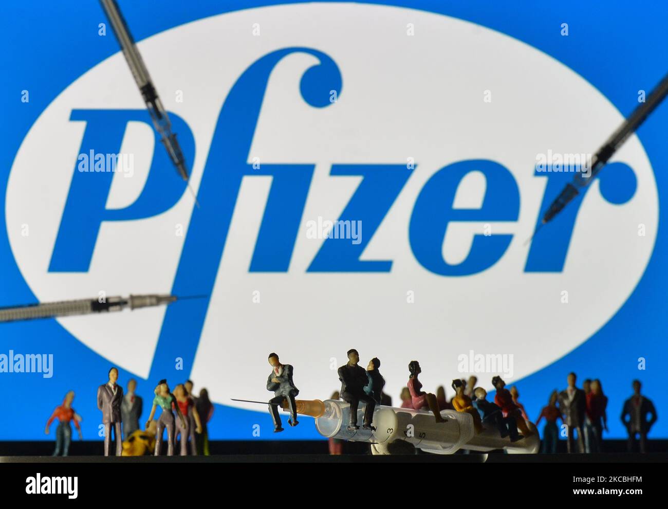 Medical syringes and small figurines of people are seen in front of the ...