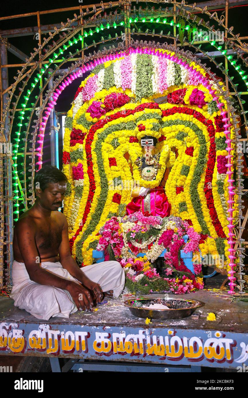 Tamil Hindu priest sits by an idol of Lord Ganesha (Lord Ganesh) as ...