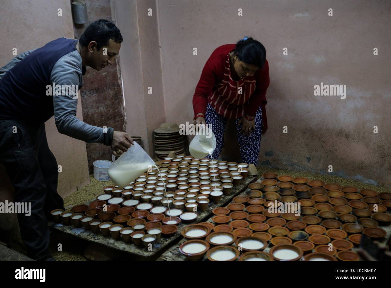 A couple pour milk into the earthen containers to prepare traditional ...