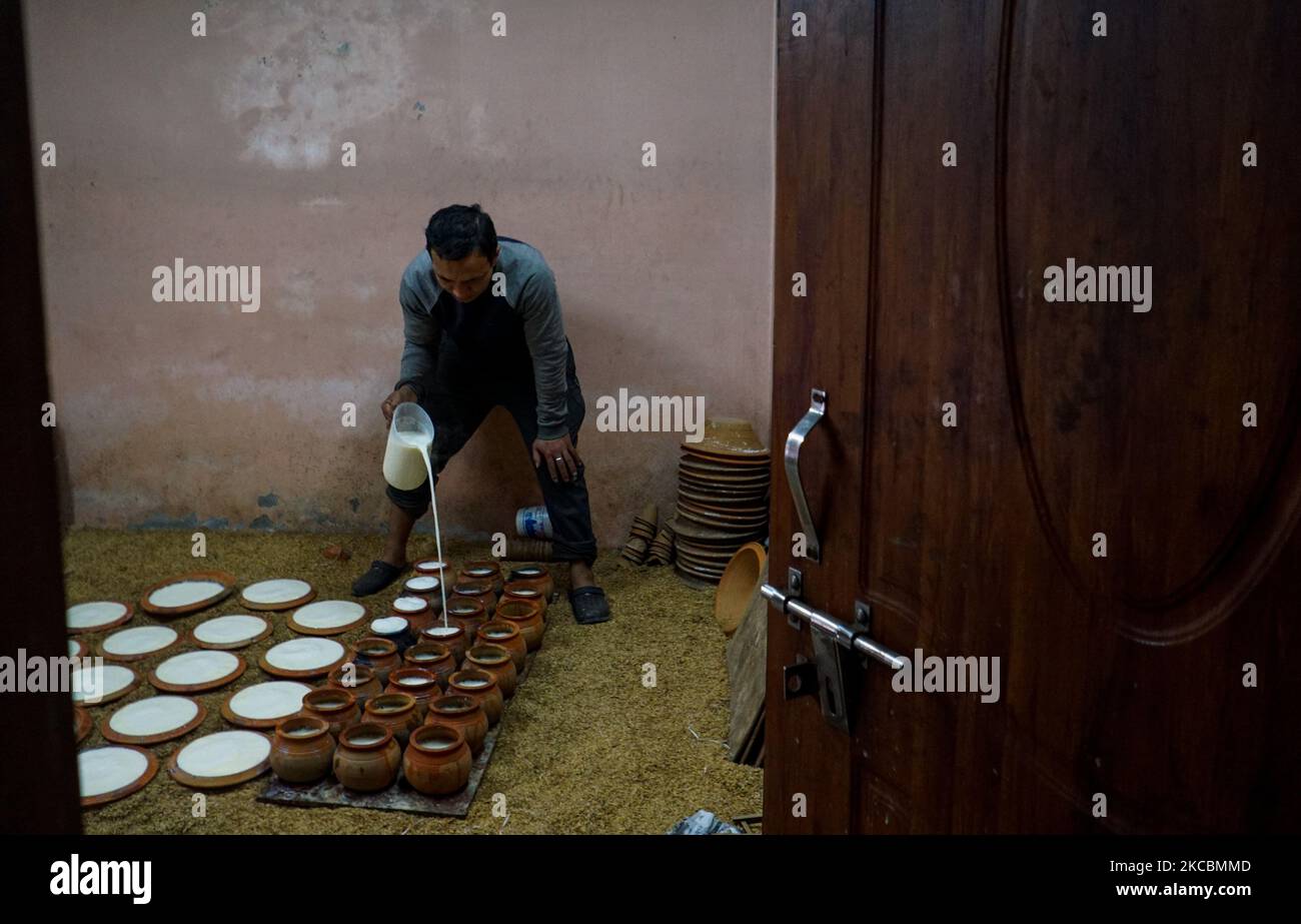 A man pours milk into the earthen containers to prepare traditional ...