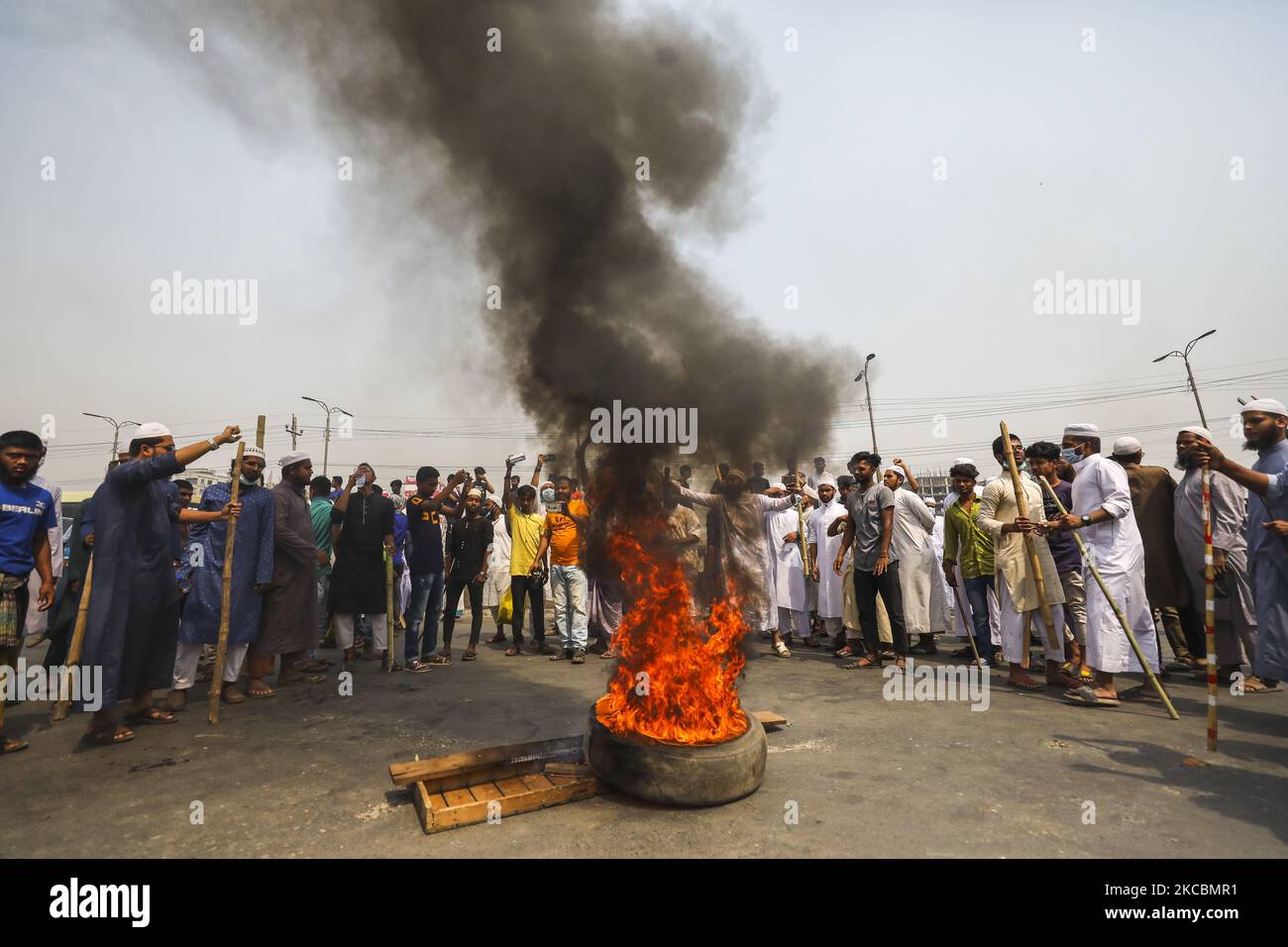 Activists from Hefazat-e Islam set fire to a tire and block a road of ...