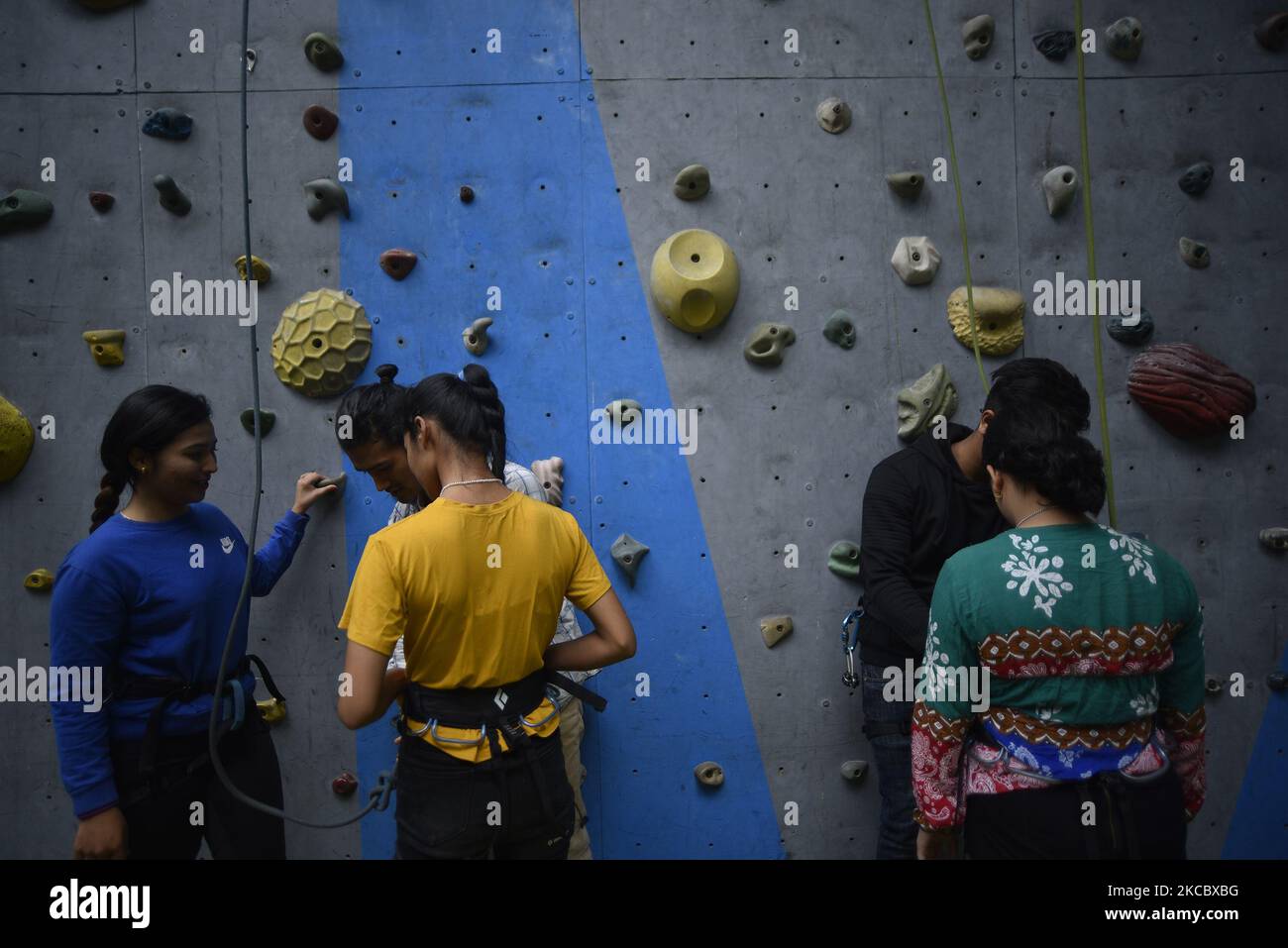 A staff helps by giving directions and guiding him to holds on the ...