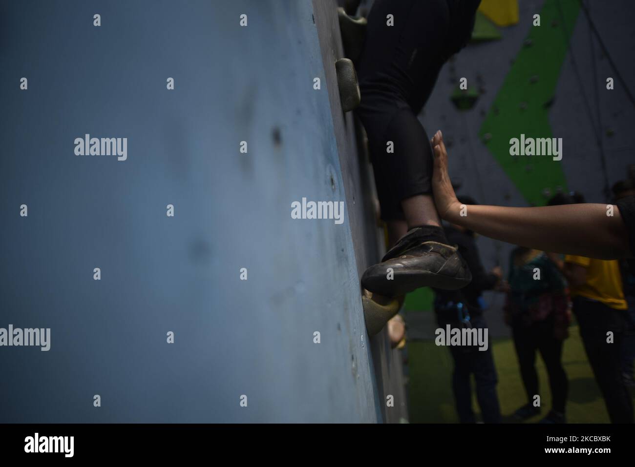 A staff helps by giving directions and guiding him to holds on the ...