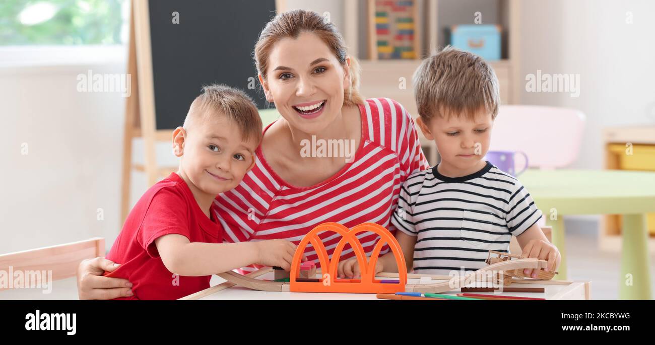 Nanny with cute little children playing at home Stock Photo - Alamy