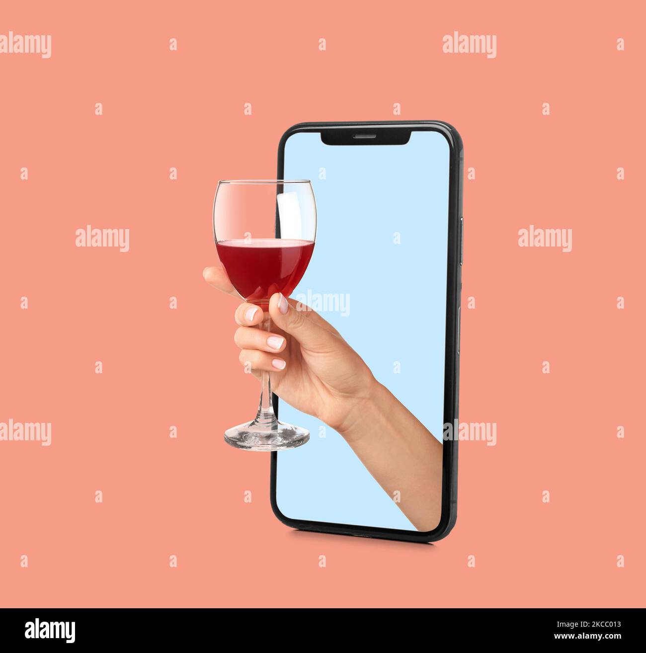 Female hand holding glass of red wine through screen of mobile phone on ...