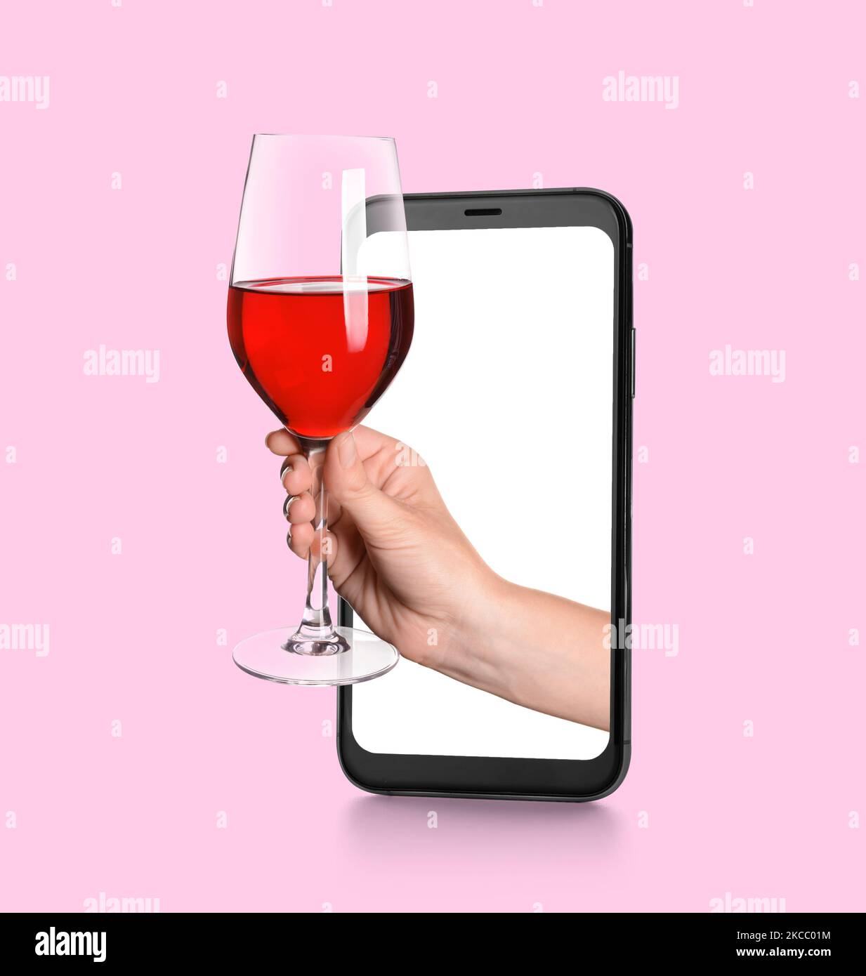 Female hand holding glass of red wine through screen of mobile phone on ...
