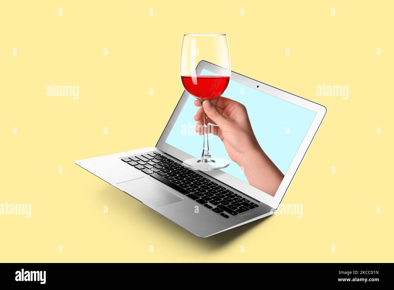 Female hand holding glass of red wine through screen of laptop on ...