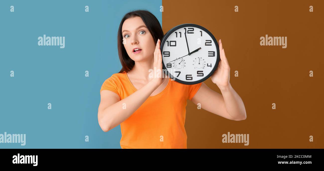 Shocked woman with alarm clock on color background Stock Photo - Alamy