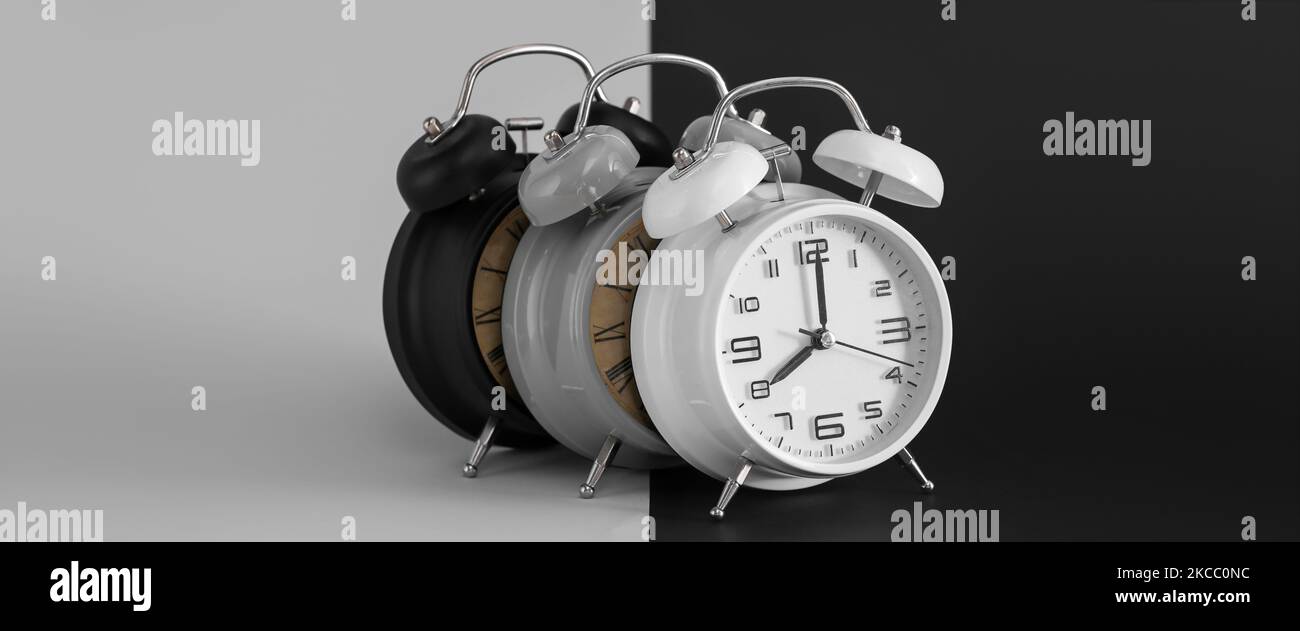 Different alarm clocks on black and white background Stock Photo - Alamy