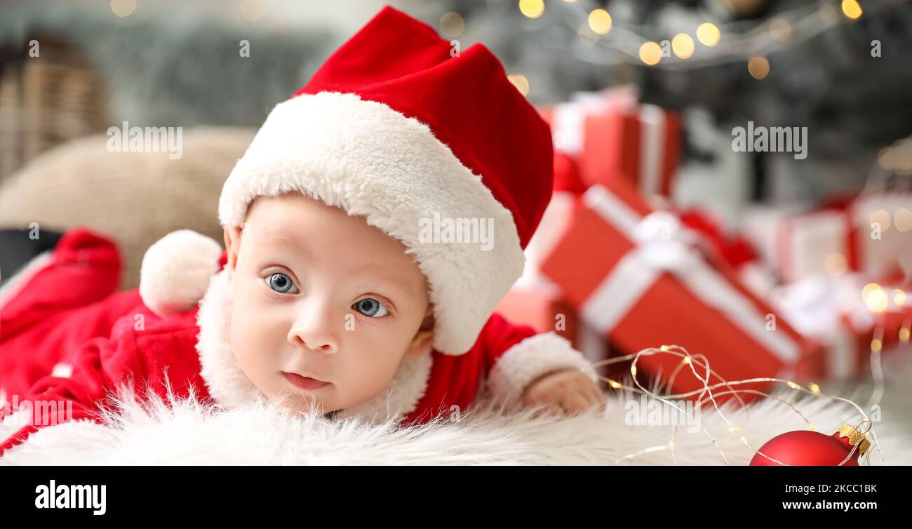 Cute little baby in Santa Claus costume lying at home on Christmas eve ...