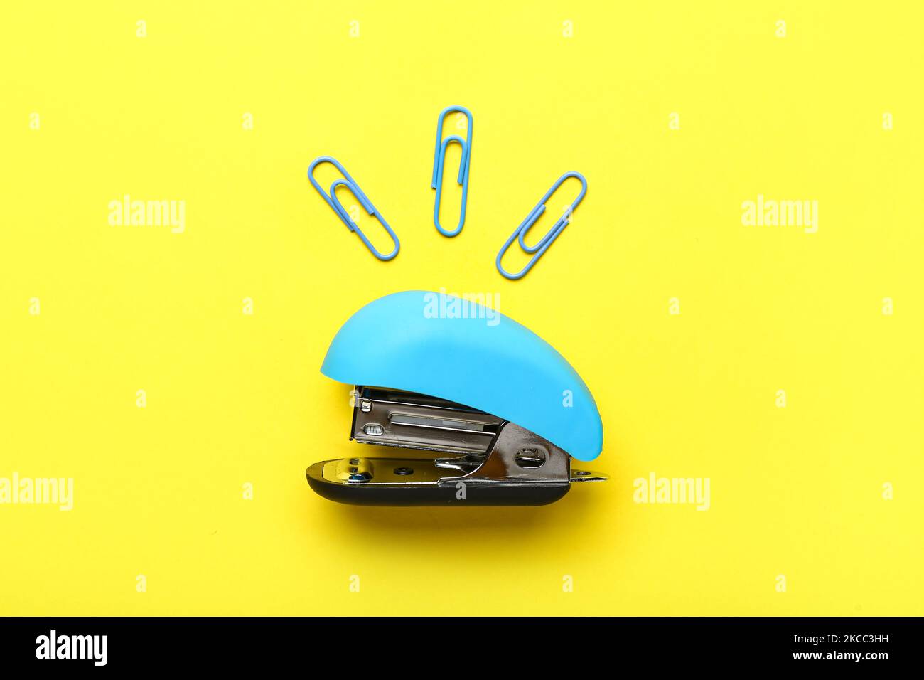 Office stapler and paper clips on yellow background Stock Photo - Alamy