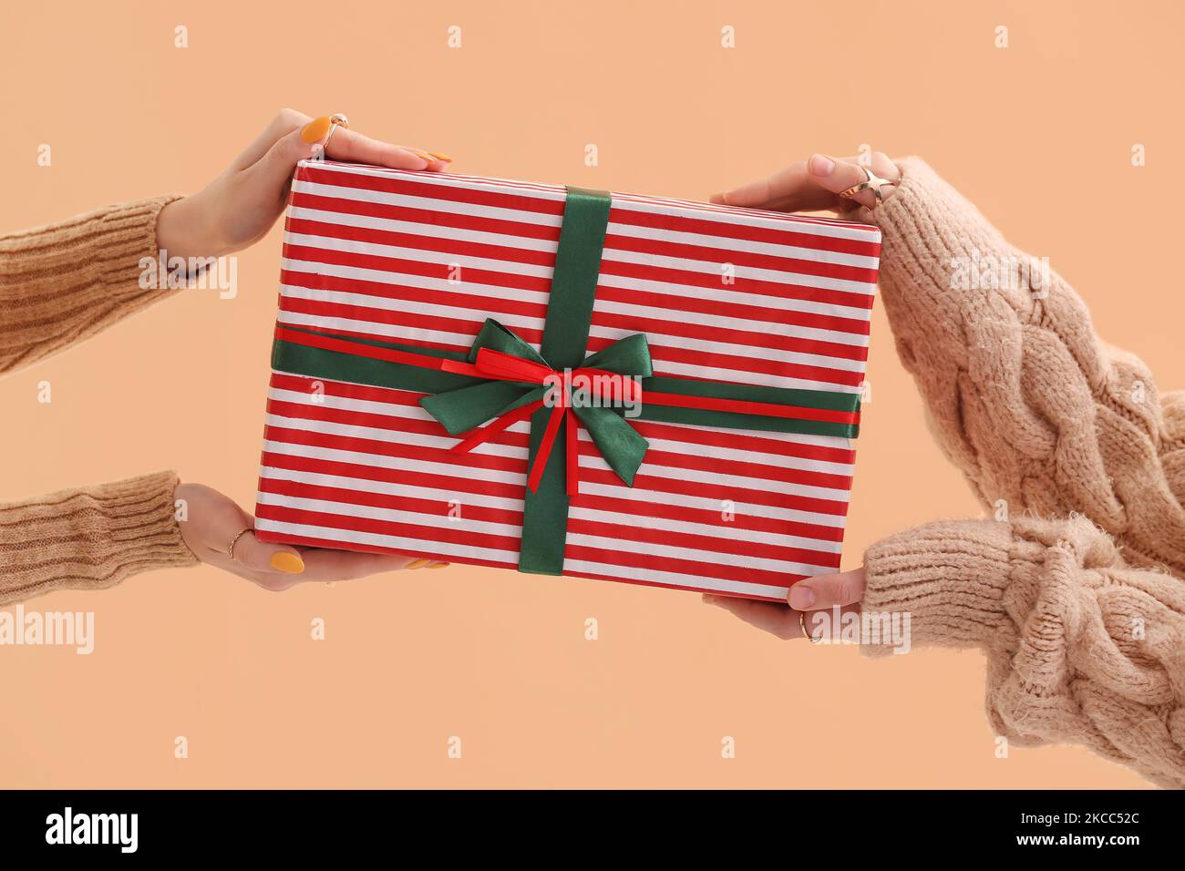Women with Christmas gift box on beige background Stock Photo - Alamy